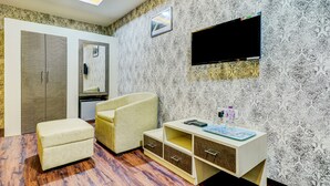 Quarto com guarda-roupa, sofá, televisão e um pequeno armário.