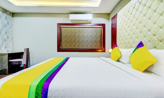 Quarto de hotel com cama, mesa de cabeceira, cadeira, parede estampada e unidade de ar condicionado.