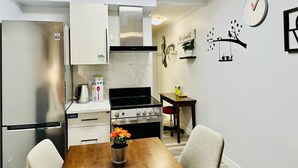 Uma cozinha moderna com forno embutido, mesa de jantar com cadeiras e um relógio na parede.