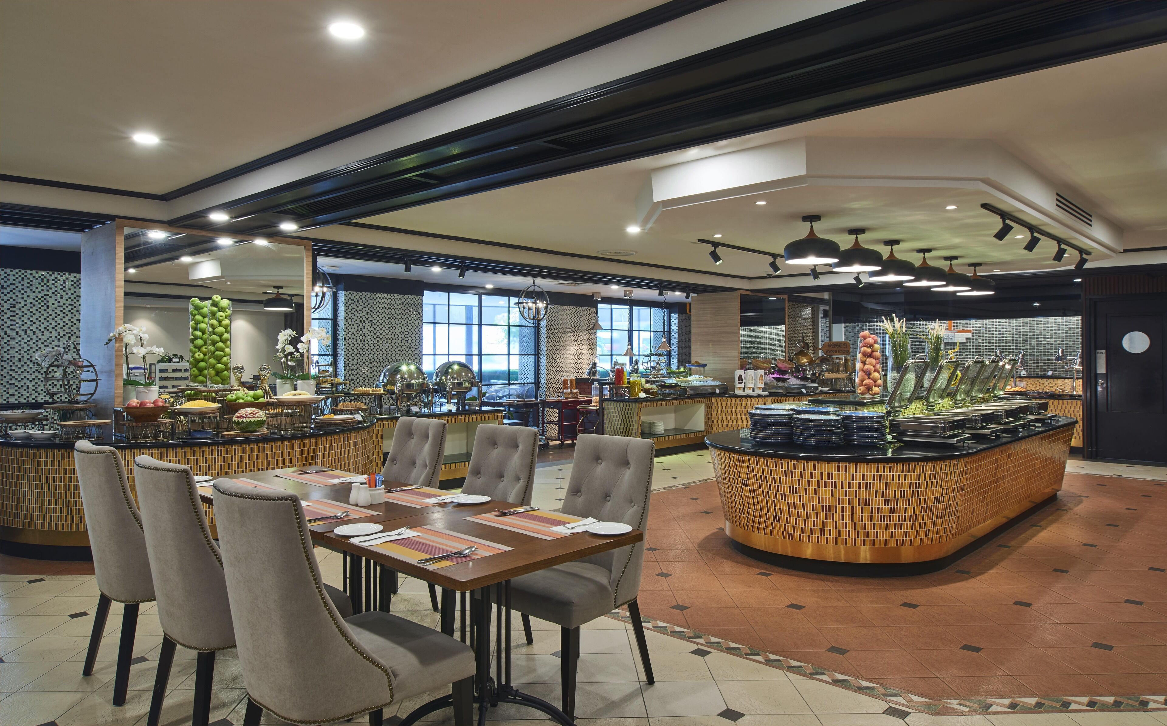 Restaurante com serviço de buffet, incluindo um balcão com diversos pratos e uma área de refeições com mesas e cadeiras.
