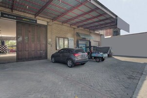 Um edifício com uma placa indicando 'Welcome Auto Bridal Club', um carro estacionado e uma área coberta com um veículo azul.
