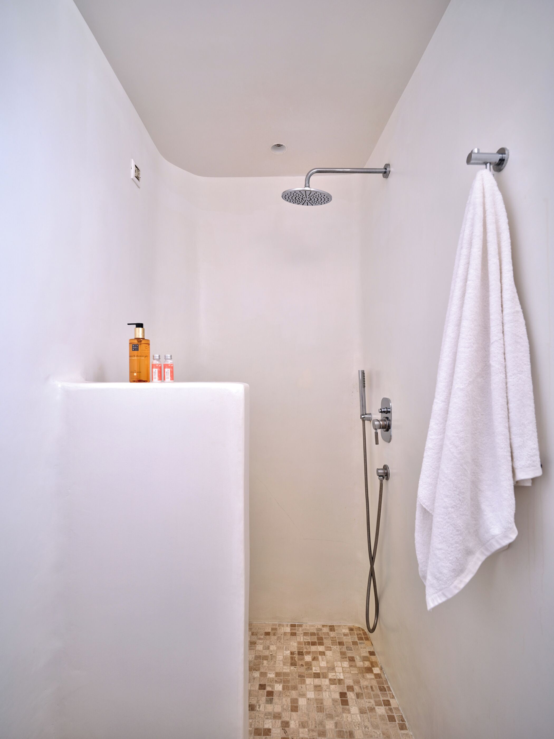 Uma casa de banho pequena e branca com chuveiro, banheira e porta-toalhas.