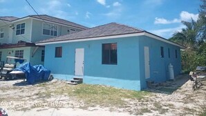 Um edifício térreo com fachada azul, porta branca e uma pequena janela.