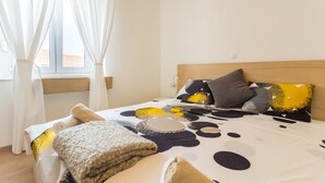 Uma cama bem arrumada com colcha estampada, cabeceira de madeira e várias almofadas.