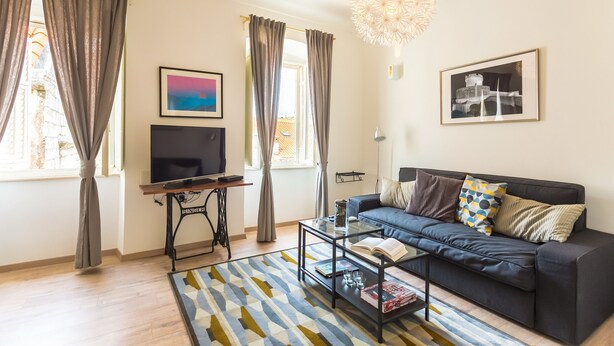 Sala de estar com sofá, mesa de centro, televisão e cortinas.