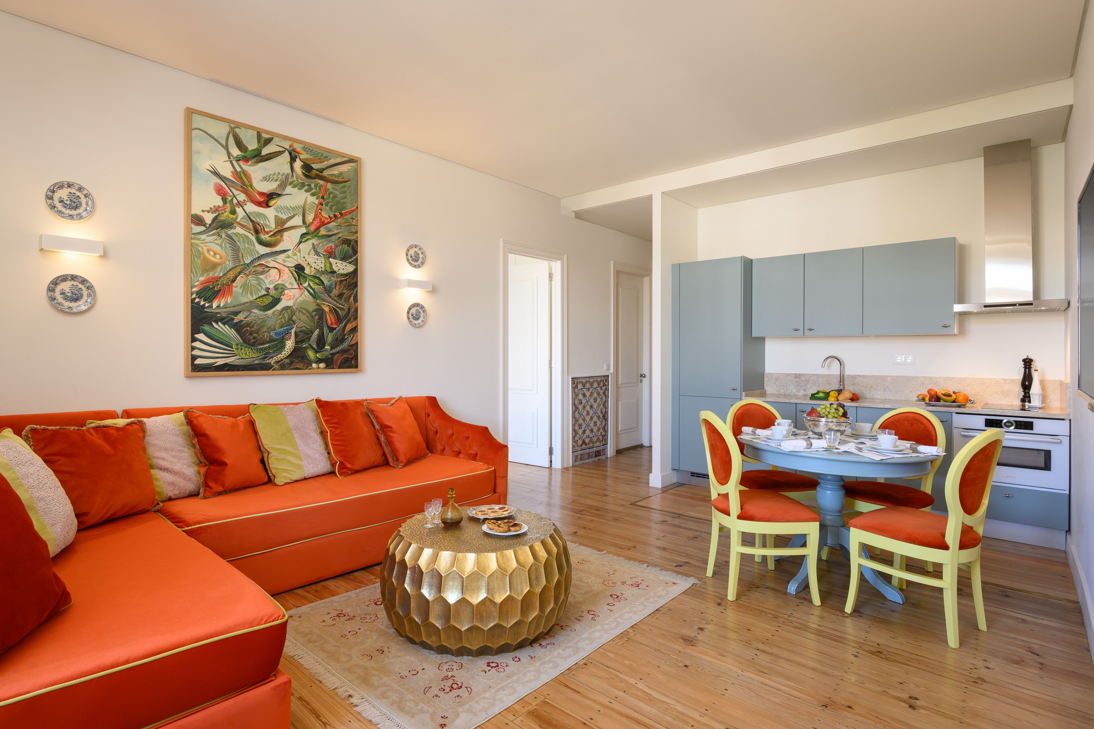 Uma sala de estar moderna com um sofá, uma mesa de centro redonda e um espaço de jantar com mesa e cadeiras.