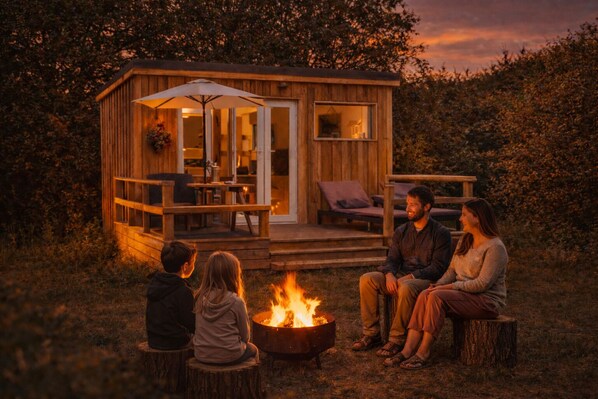Uma cabana de madeira com varanda, lareira e uma pequena área de estar ao ar livre.