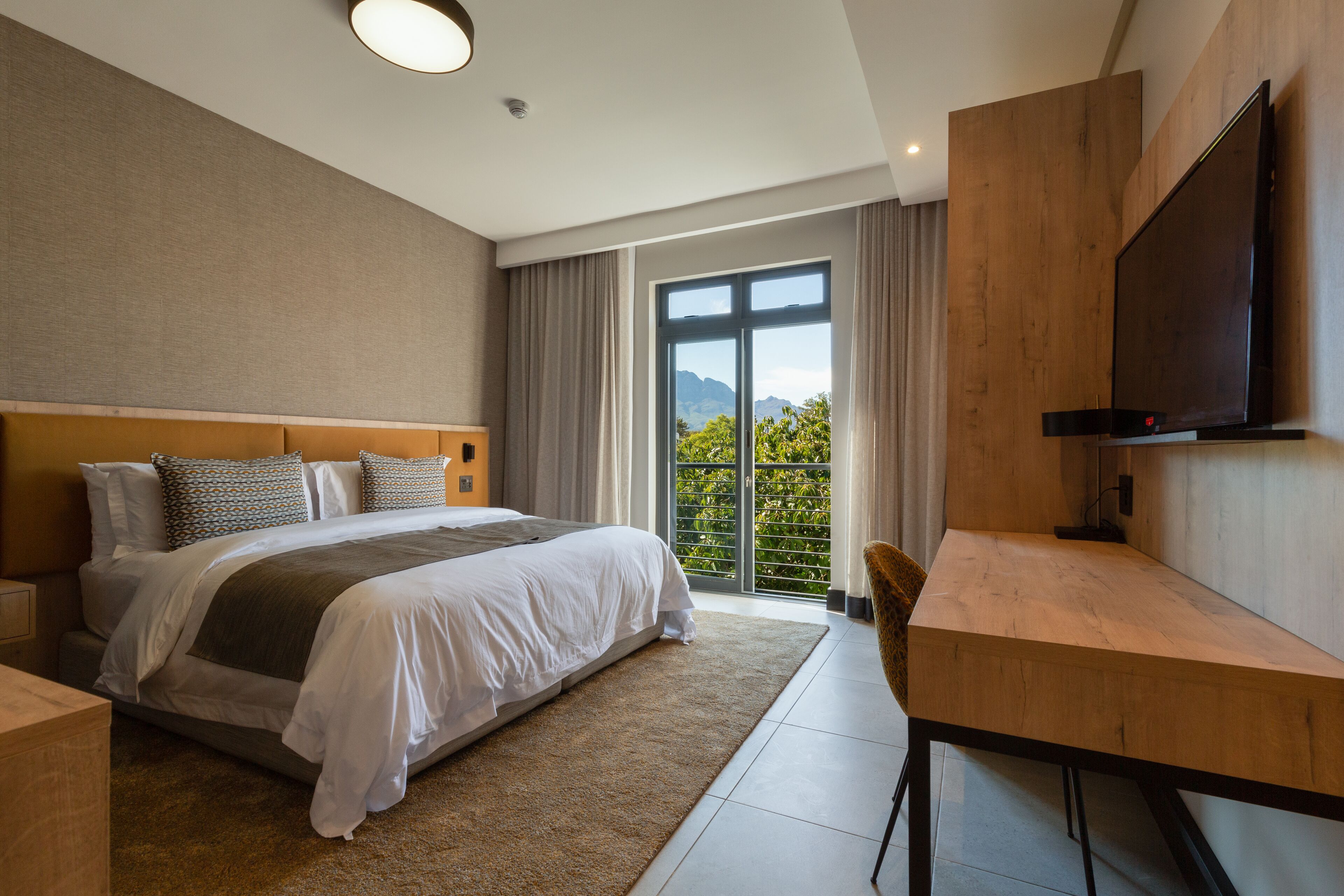 Quarto de hotel moderno com uma cama grande, uma escrivaninha e uma televisão.