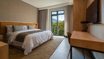 Quarto de hotel moderno com uma cama grande, uma escrivaninha e uma televisão.