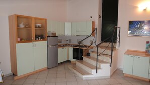Cozinha com armários verde-claros, uma geladeira de aço inoxidável e piso ladrilhado.