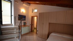 Quarto com cama, guarda-roupa, escrivaninha e um quadro na parede.