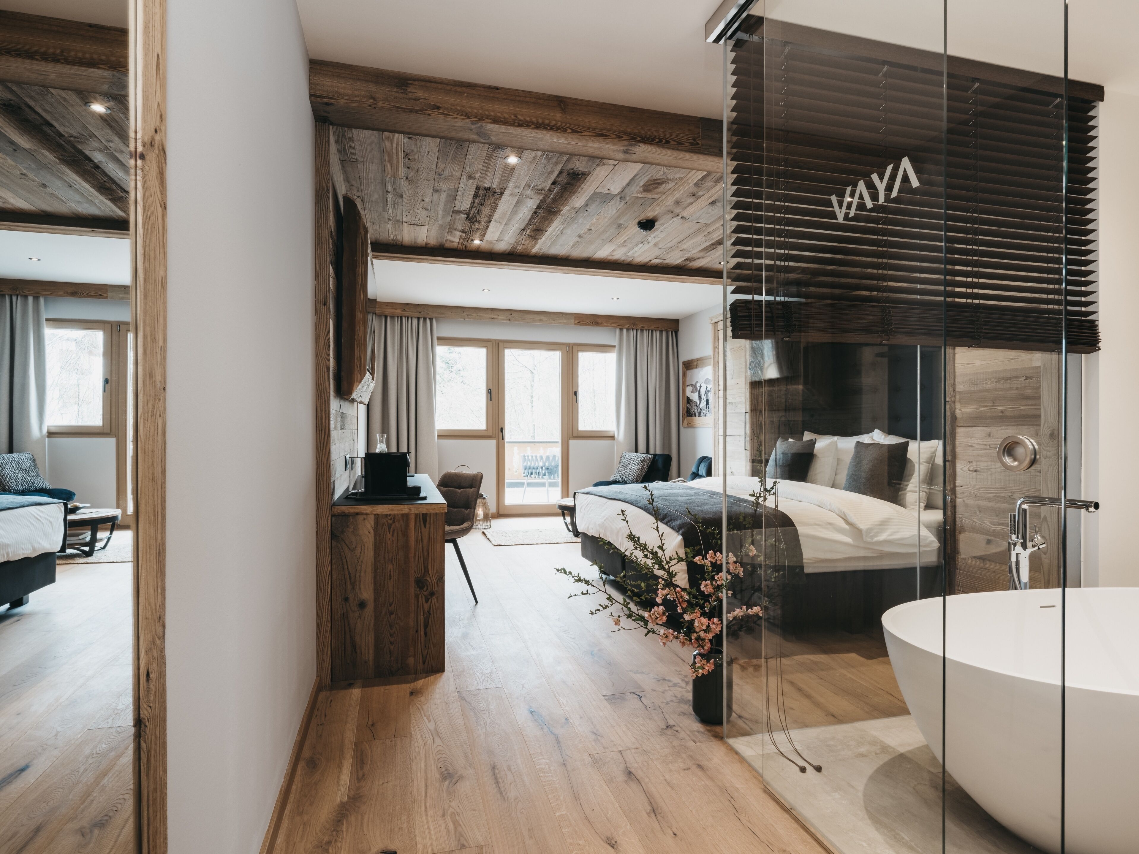 Quarto moderno com uma cama grande, um chuveiro envidraçado e teto de madeira.