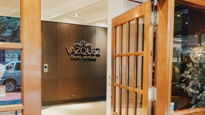 Entrada de hotel com porta de madeira e placa com a inscrição 'Vazquez Grupo Hotelero'.