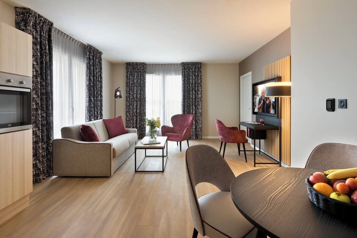 Uma sala de estar moderna com um sofá, cadeiras, uma mesa de centro e um espaço de jantar com mesa e cadeiras.