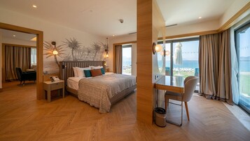 Um quarto espaçoso com uma cama grande, uma escrivaninha e vista para o mar.