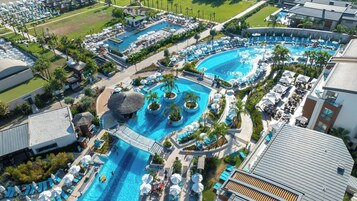 Resort com várias piscinas, espreguiçadeiras e palmeiras.