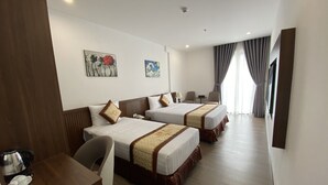 Quarto de hotel com duas camas, uma escrivaninha com chaleira e uma cadeira.