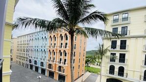Um edifício de vários andares com um pátio central, apresentando uma palmeira e um candeeiro.