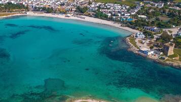 Vista aérea de uma cidade costeira com praia, águas turquesa cristalinas e edifícios residenciais.