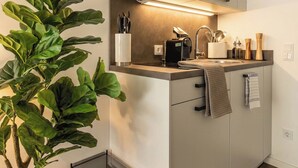 Uma cozinha moderna com armários brancos, bancada, pia e um vaso com planta.