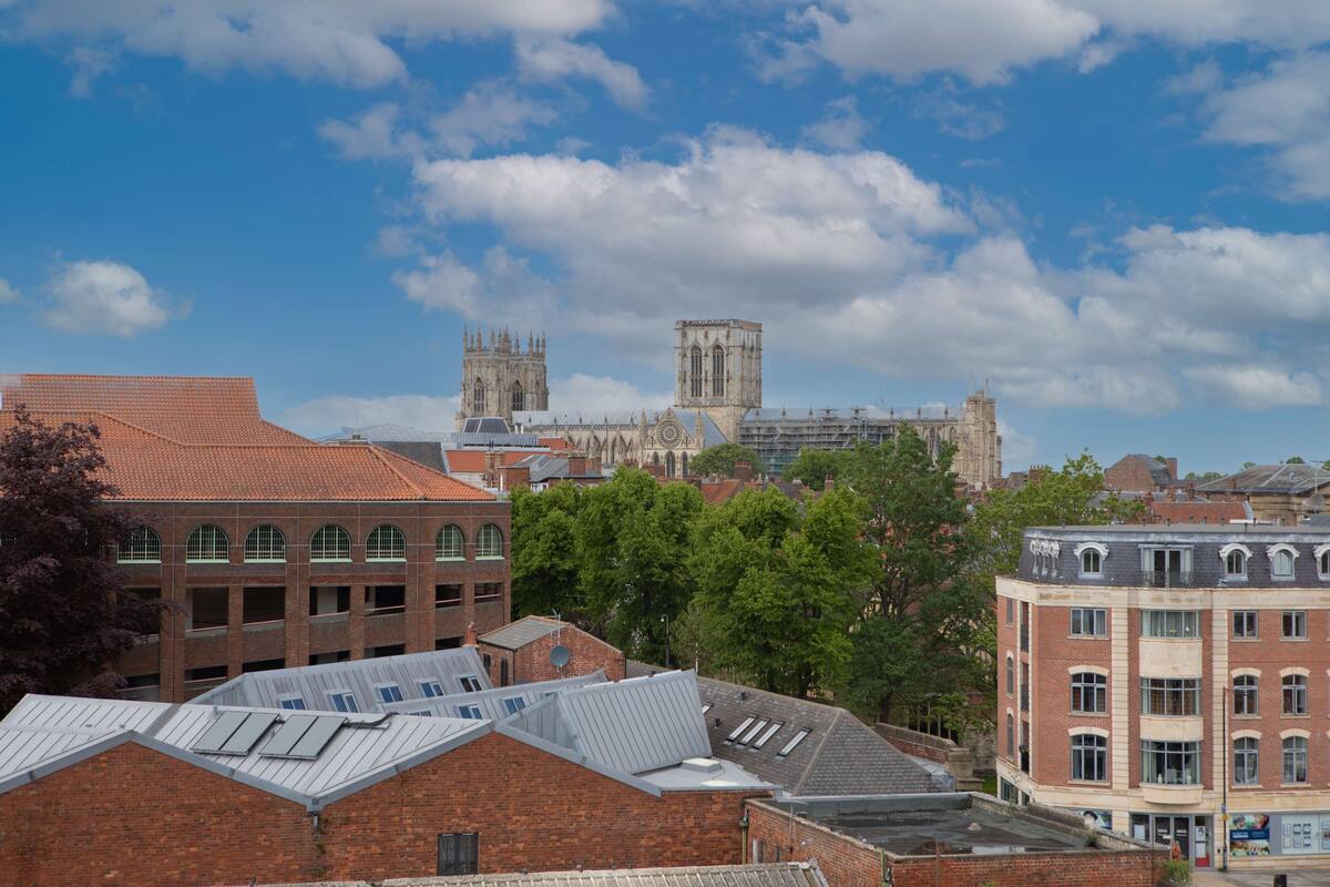 Vista de um edifício histórico com uma torre imponente e uma catedral ao fundo.