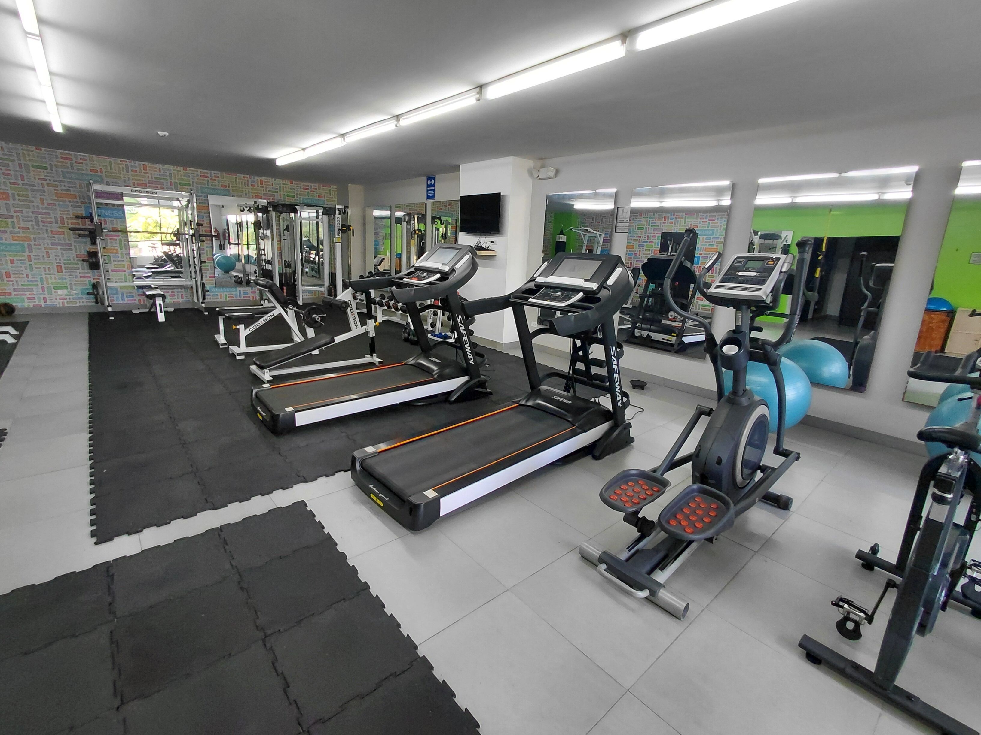 Uma academia com esteiras, elípticos e equipamentos de musculação.