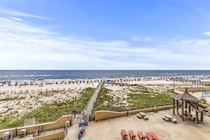 Vista da praia com calçadão, guarda-sóis e cadeões de praia.