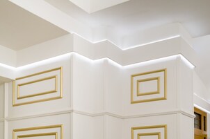 Um quarto com paredes brancas e detalhes dourados nas portas e cantos.