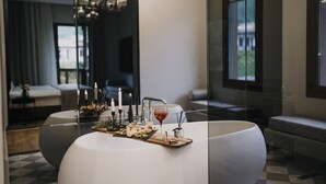 Um interior moderno com uma mesa central exibindo uma taça de vinho tinto, velas e petiscos.