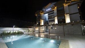 Um hotel com piscina, arquitetura moderna e fachada bem iluminada.