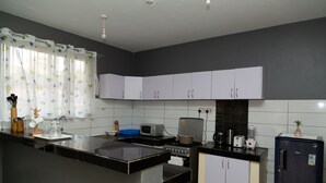 Uma cozinha moderna com ilha central, armários brancos, micro-ondas, fogão e geladeira.