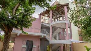 Um edifício residencial com várias andares, fachada rosa, varandas e uma escadaria central.