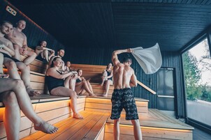 Uma sauna com bancos de madeira e uma pessoa se secando com uma toalha.