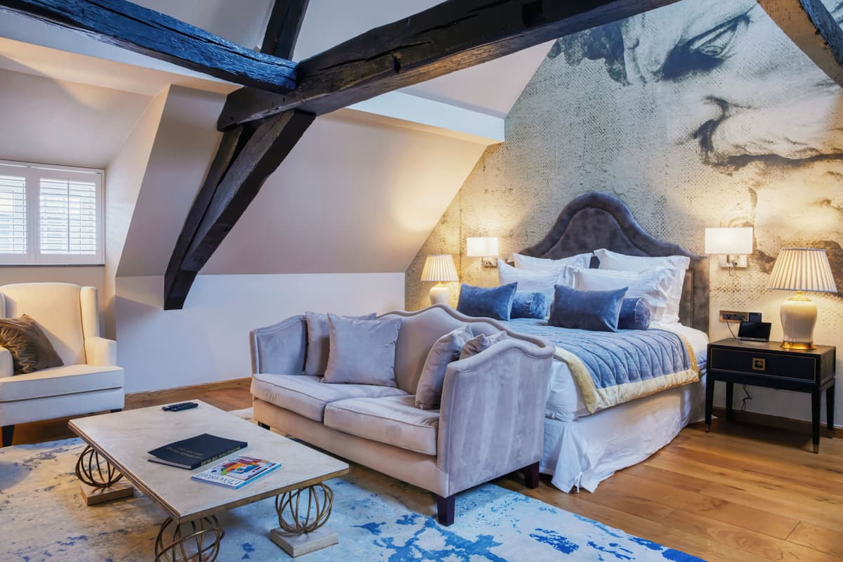 Um quarto com uma cama, um sofá, uma mesa de cabeceira e uma luminária.