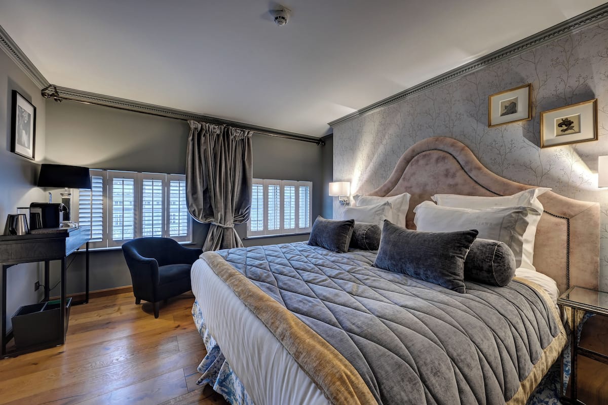 Quarto com uma cama grande, uma escrivaninha, uma cadeira e uma janela com cortinas.