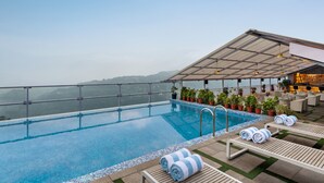 Piscina infinita no terraço, com espreguiçadeiras e plantas em vasos.