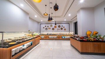 Uma área de buffet moderna com várias estações de comida, balcões de madeira e iluminação pendente.