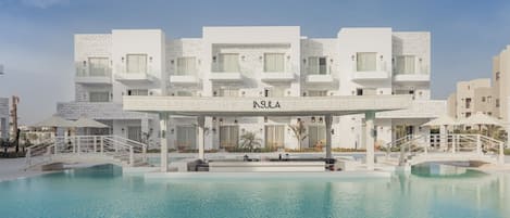 Um hotel moderno com área de piscina, apresentando uma entrada coberta e várias varandas.