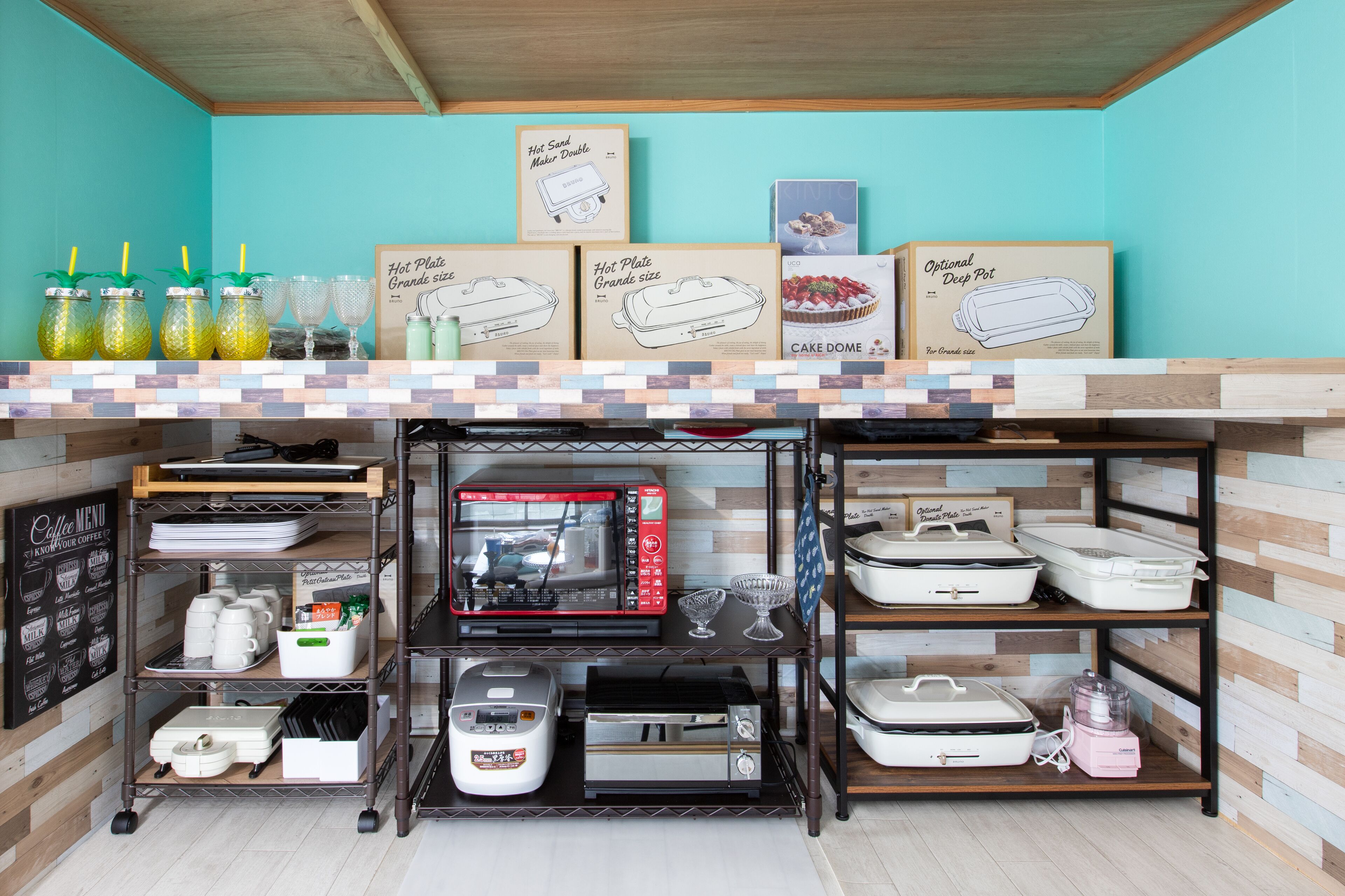 Cozinha equipada com diversos eletrodomésticos e utensílios, incluindo micro-ondas, torradeira e cafeteira, além de recipientes de armazenamento identificados e um dome para bolo.