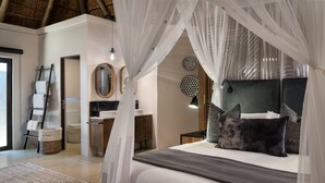 Quarto com cama de dossel, toucador com espelho e banheiro pequeno com porta-toalhas e escada.