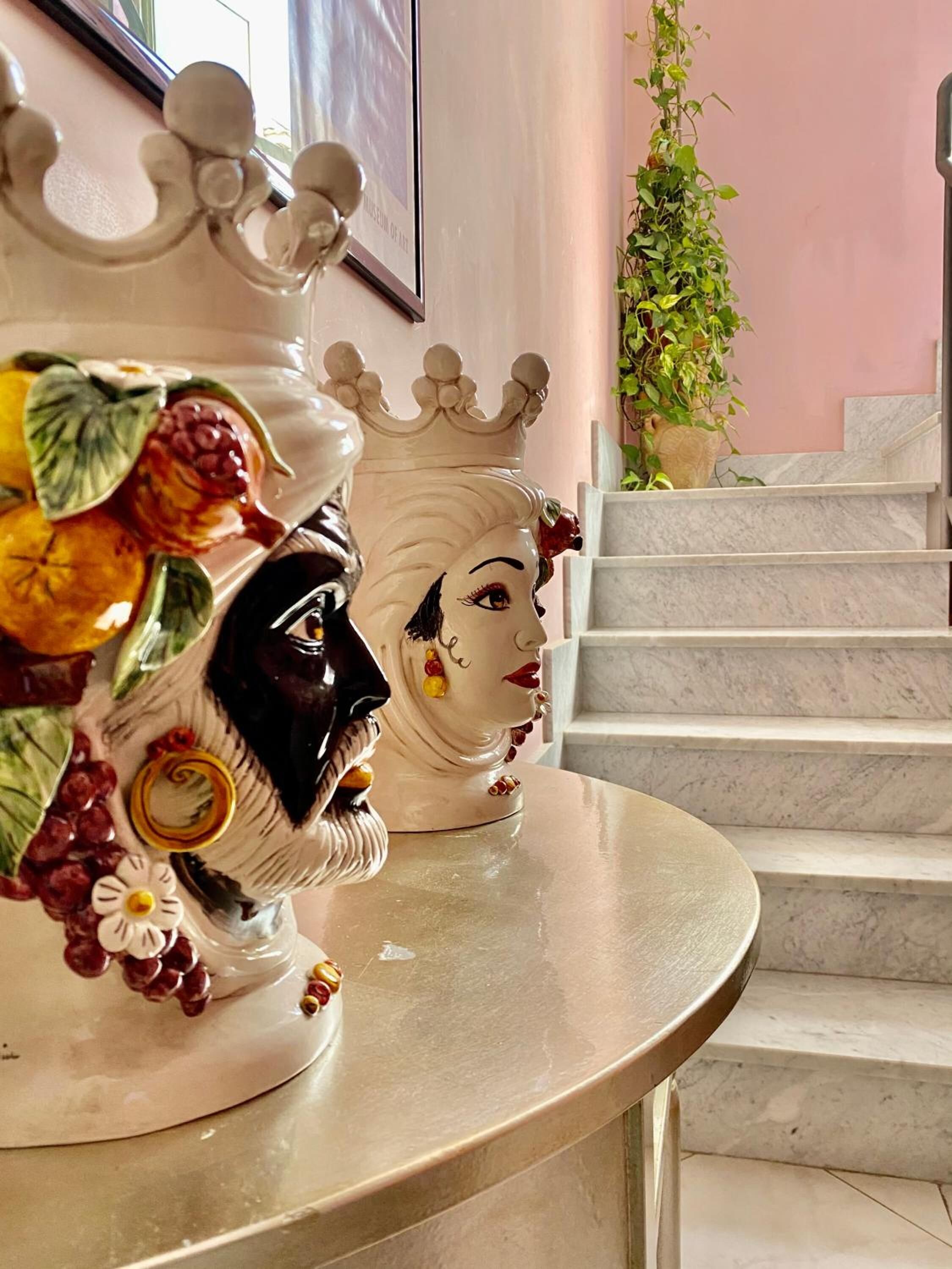 Uma peça de cerâmica decorativa com motivos florais e de frutas em uma superfície curva.