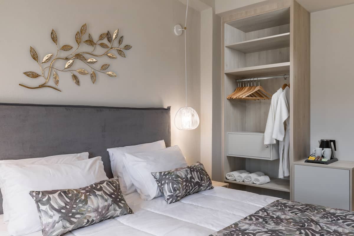 Quarto de hotel com cama, guarda-roupa e uma obra de arte na parede.