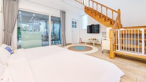 Um quarto espaçoso com uma cama grande, uma escada de madeira e uma televisão.