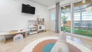 Um quarto de brincar infantil com televisão, cozinha de brinquedo e brinquedos.