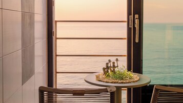 Uma varanda com mesa e cadeiras, com vista para um corpo d'água.