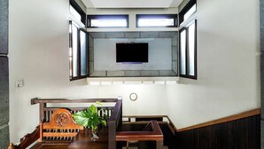 Um interior moderno com televisão de tela plana na parede, mobiliário de madeira e uma escada com painéis de madeira escura.