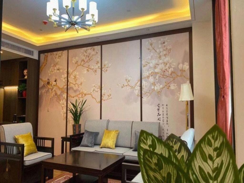 Uma sala de estar moderna com sofá, cadeiras, mesa de centro e parede decorativa com padrões florais.