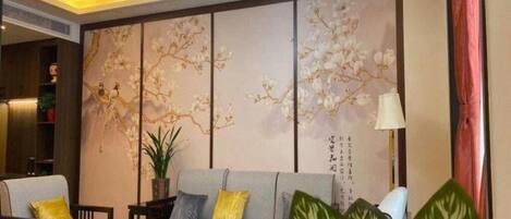 Uma sala de estar moderna com sofá, cadeiras, mesa de centro e parede decorativa com padrões florais.