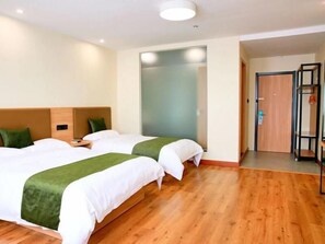 Quarto de hotel com duas camas, piso de madeira e um guarda-roupa.