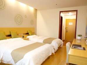 Quarto de hotel com duas camas, uma escrivaninha e uma cadeira. Há uma porta que dá para outro quarto.